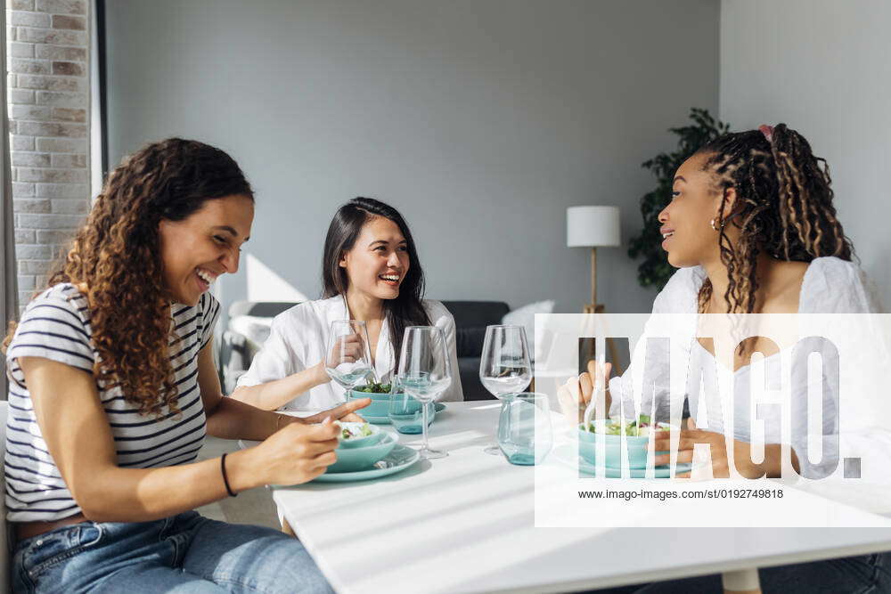 Cheerful Friends Having Salad At Dining Table In Living Room Model