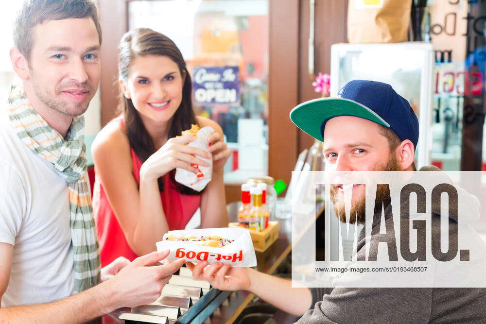 Hotdog - young customers in a snack bar eating delicious fast food ...