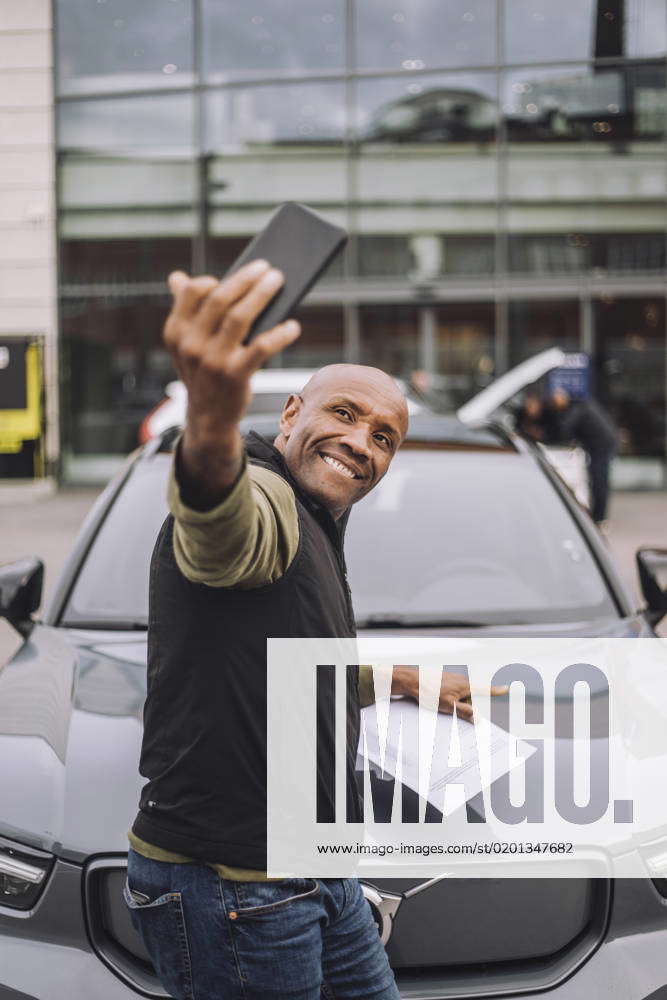 Glad man tar bild pa sig själv och bil med