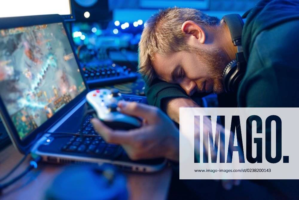Male gamer with joystick in hands sleeping at his laptop after ...