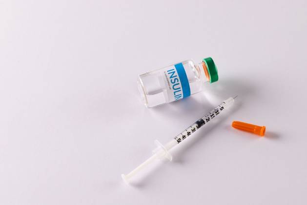 Insulin vial and uncapped syringe on white background with copy space ...