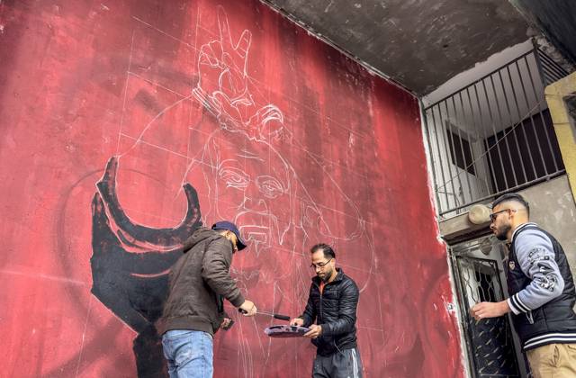 Palestinian artists work by a mural shows jailed Fatah leader Marwan ...