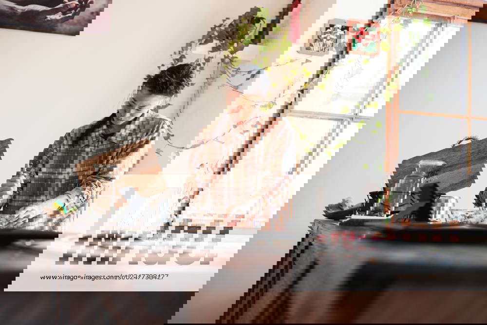 View along wooden bench of person baking cookies from recipe at home ...