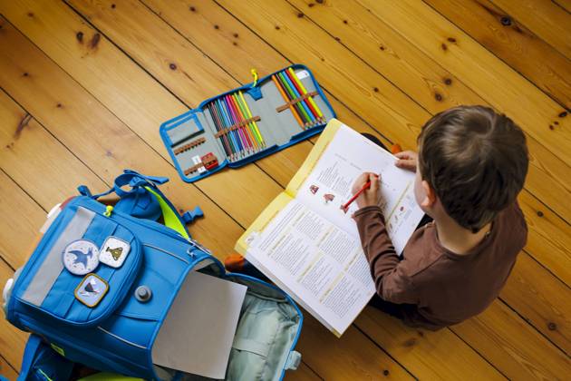 Homework at home symbol photo A boy sits on the floor doing homework ...