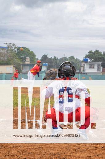 A male baseball player in motion mid-pitch, throwing the ball with a ...