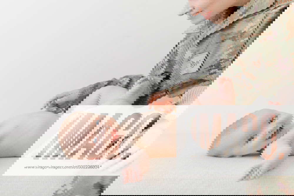 Active duty military mom playing with baby as she changes his diaper ...