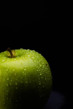 Micro close up of green apple with water drops and copy space on black ...