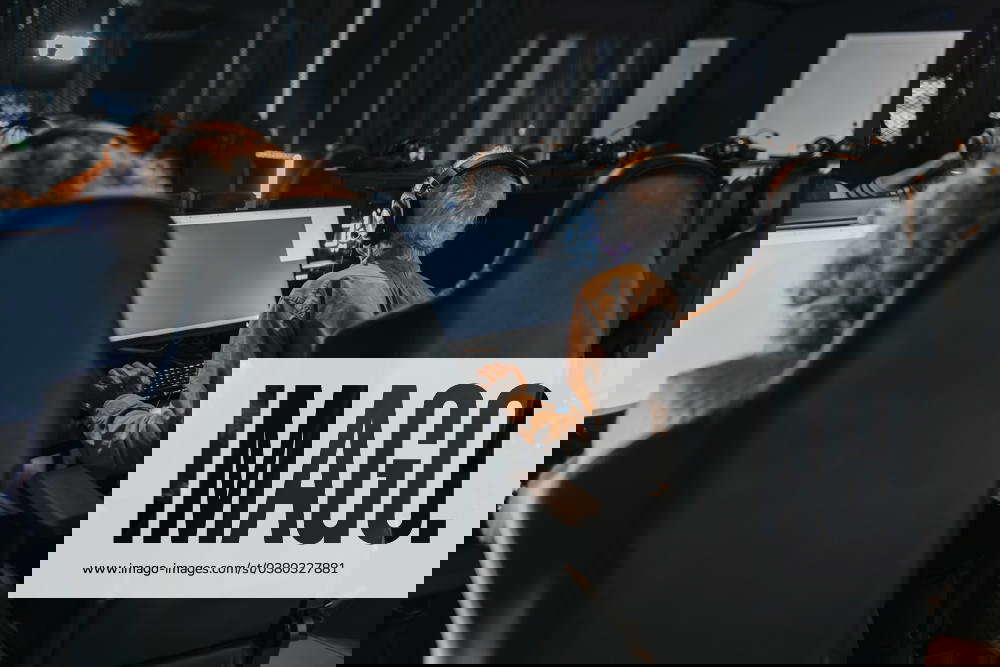 Rear view of male and female friends playing game over computers while ...