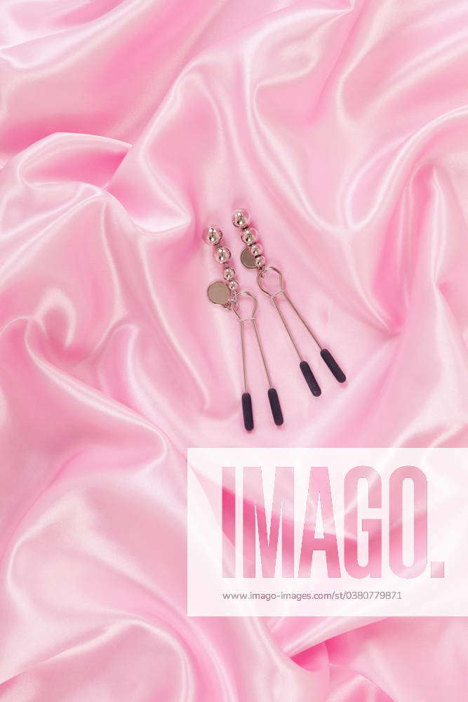 Nipple clamps on pink top view. Nipple clamps on pink satin fabric, top ...