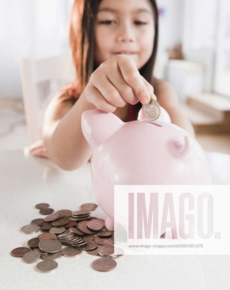 Mixed race girl putting coin in piggy bank Jersey City, NJ, 21.12.2023 ...
