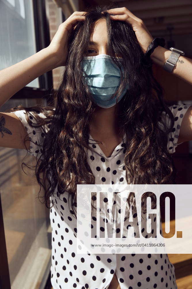 Portrait of young ethnic woman with face mask wearing polka dot blouse ...