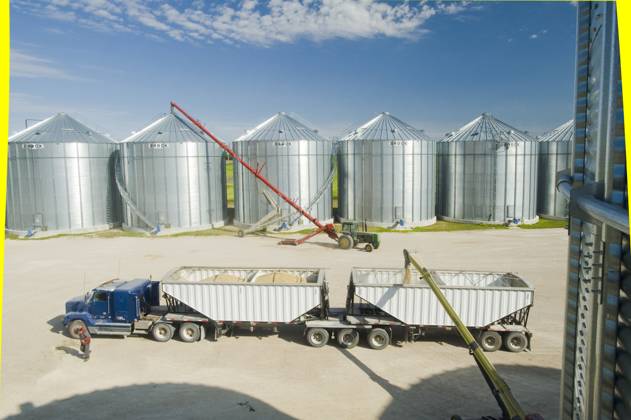 A super B grain truck being loaded with barley from grain storage bins ...