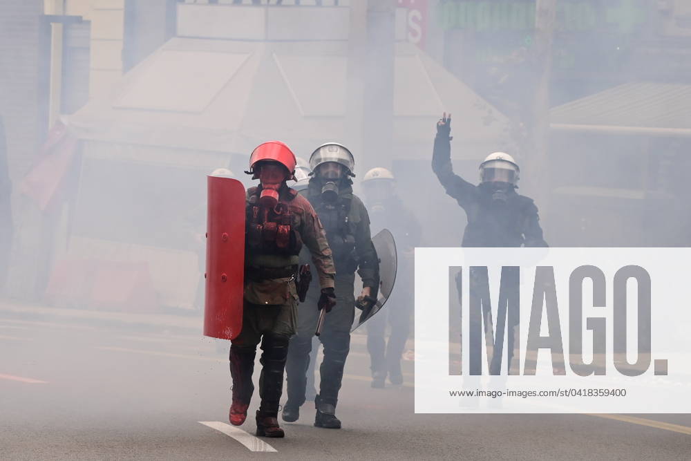 Riot police officer covered in red paint walks along with other ...