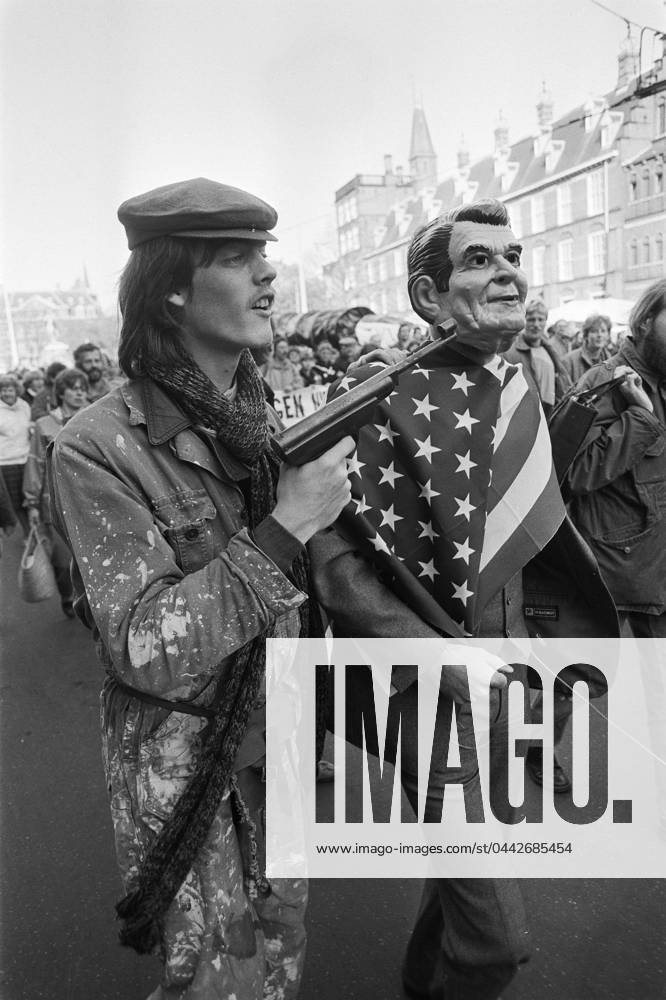ANTI-REAGAN PROTESTER, 1983. A protester holding a gun at a man in a ...