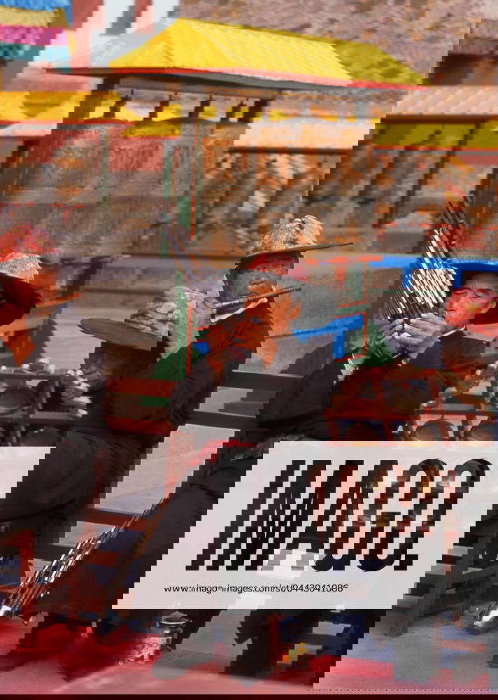 China: A musician using a sheng in front of the main hall housing the ...