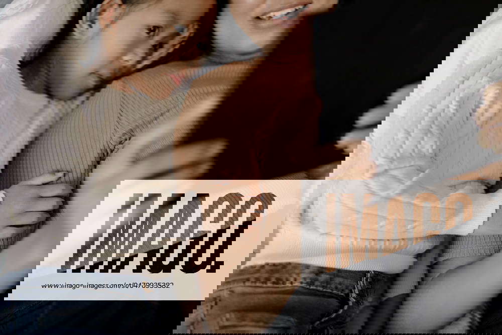 Woman sharing digital tablet with daughter while sitting on bed at home Sweden, Stockholm, model