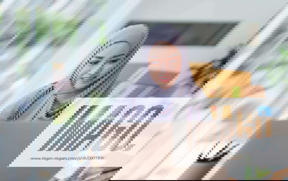 Beautiful Muslim woman using computer to check customer orders, small business owners or sme