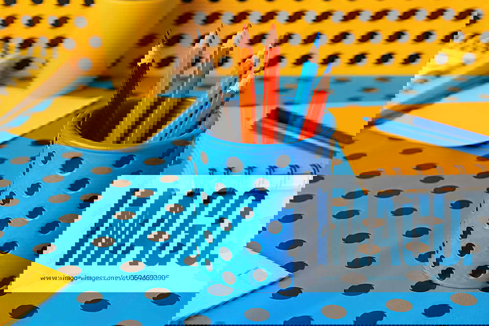 A blue pencil holder with polka dots sits on a blue polka dot desk with ...