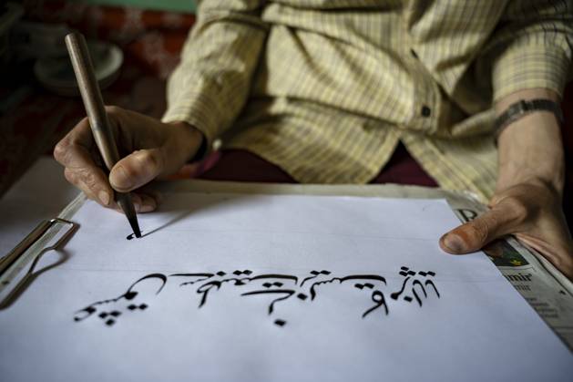 Srinagar, Jammu And Kashmir, India: A calligrapher uses a tipped wooden ...