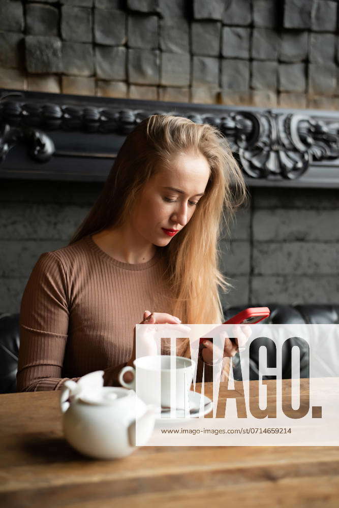 Young female blogger with a phone in a restaurant drinking tea Rivne, Rivne Oblast, Ukraine