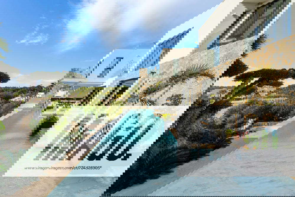 Elegant modern villa featuring a stunning pool with a garden view, stylish outdoor seating, and