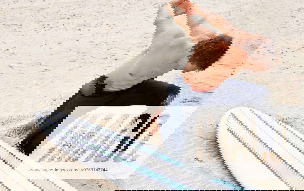 Surfer, man is stretching and beach sand with surfboard for ocean waves ...