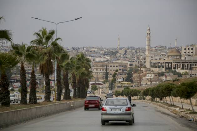 Syrian Civil War Cars drive down a road with the historic Hama skyline ...